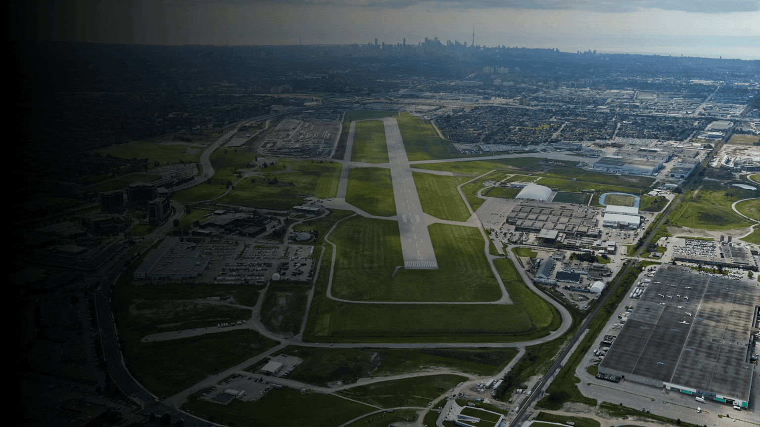 Airport runway with city skyline in background.
